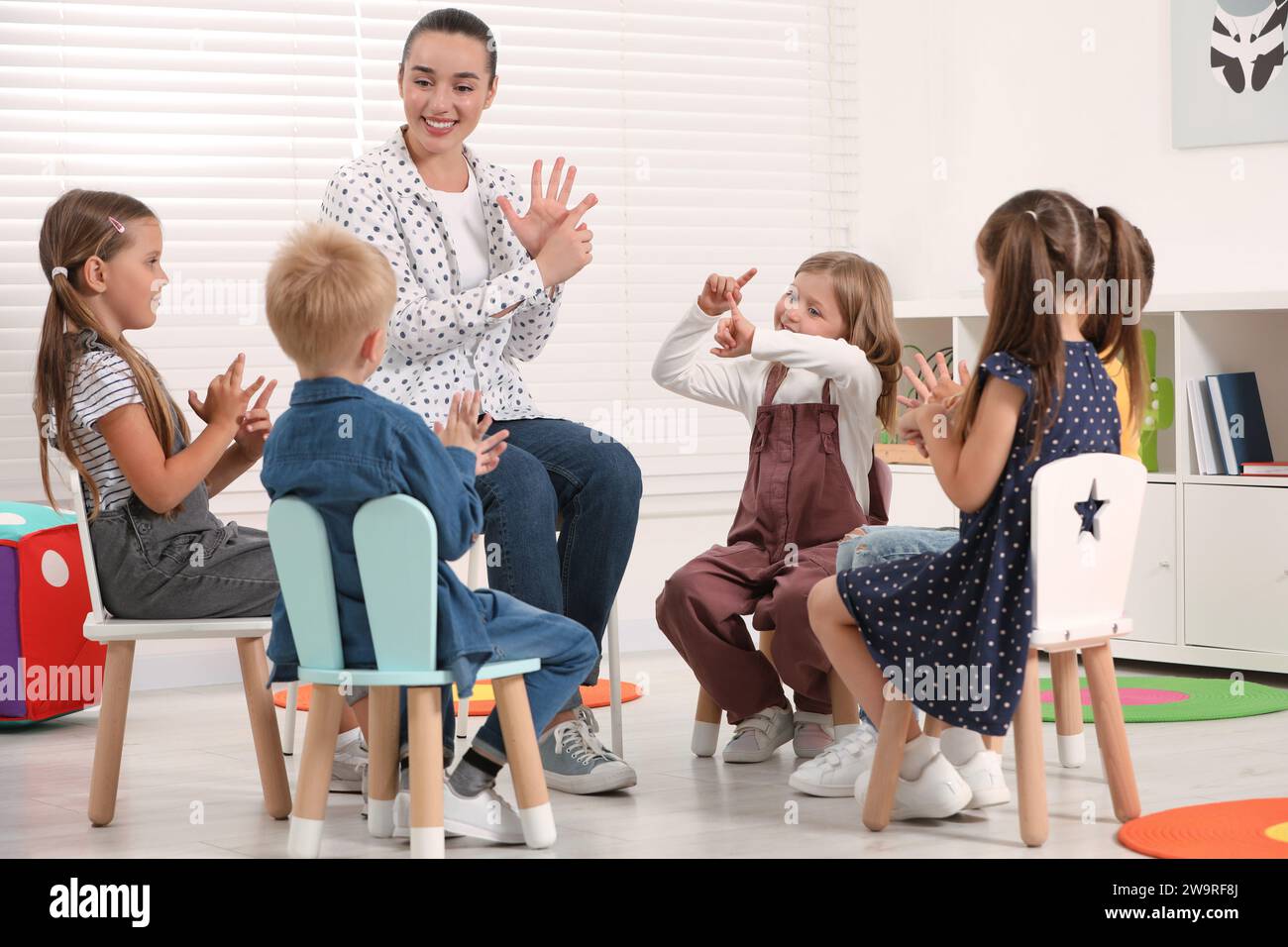 Nursery teacher and group of cute little children learning numbers in ...
