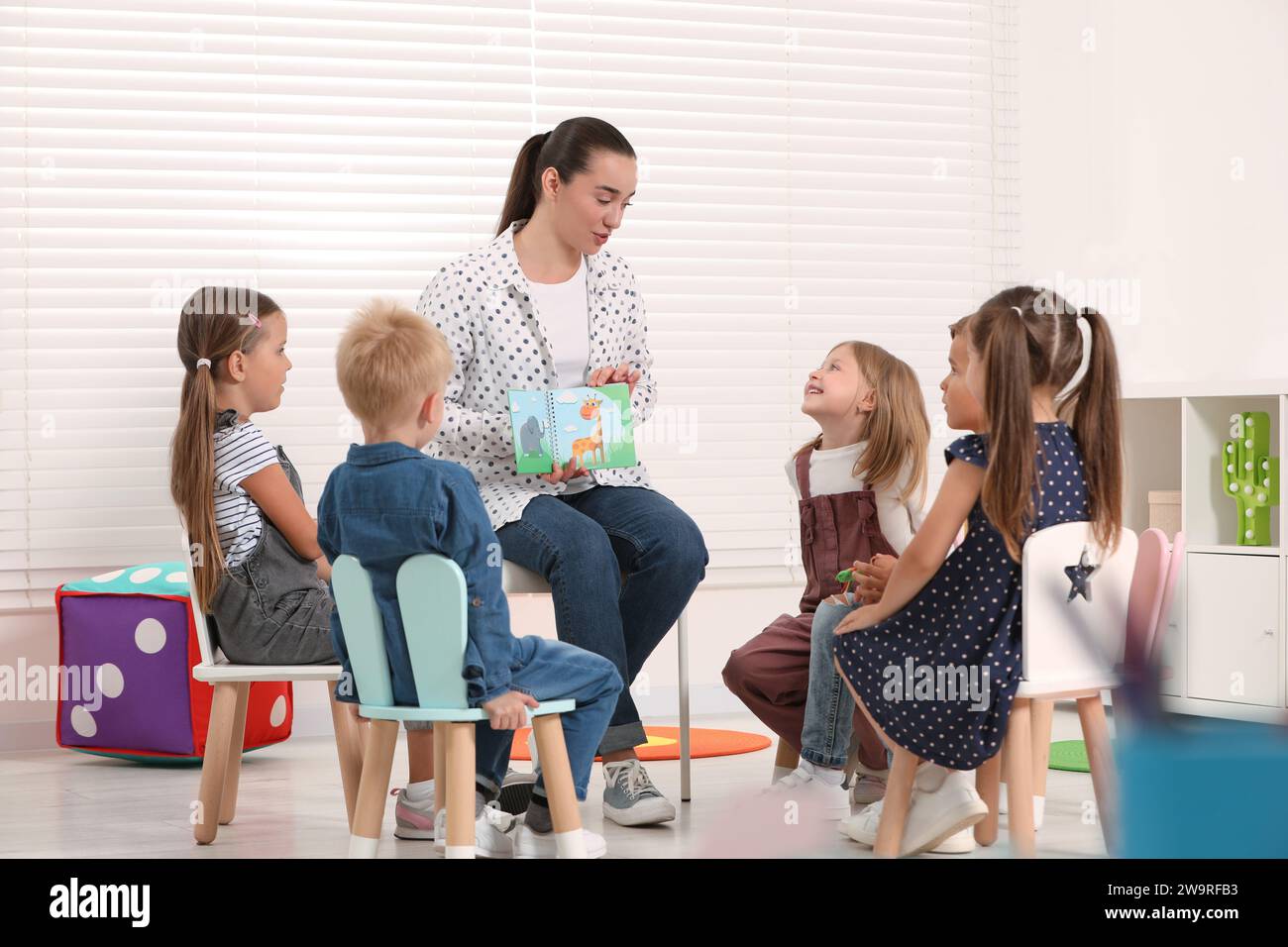 Nursery teacher and group of cute little children learning animals in ...