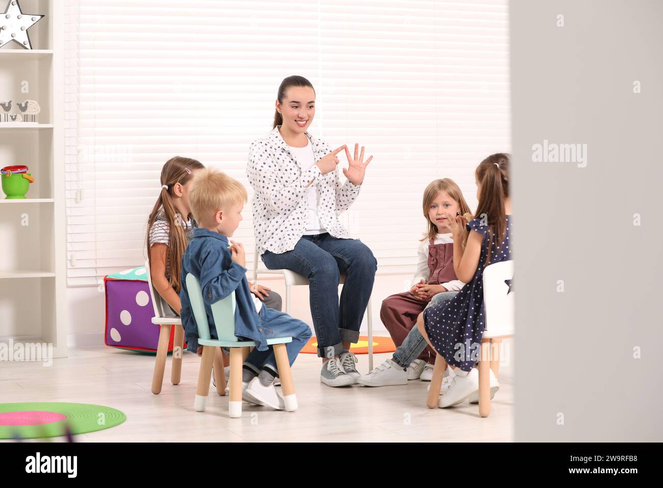 Nursery teacher and group of cute little children learning numbers in ...