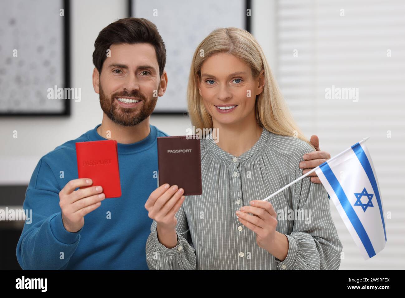 Immigration. Happy couple with passports and flag of Israel indoors ...