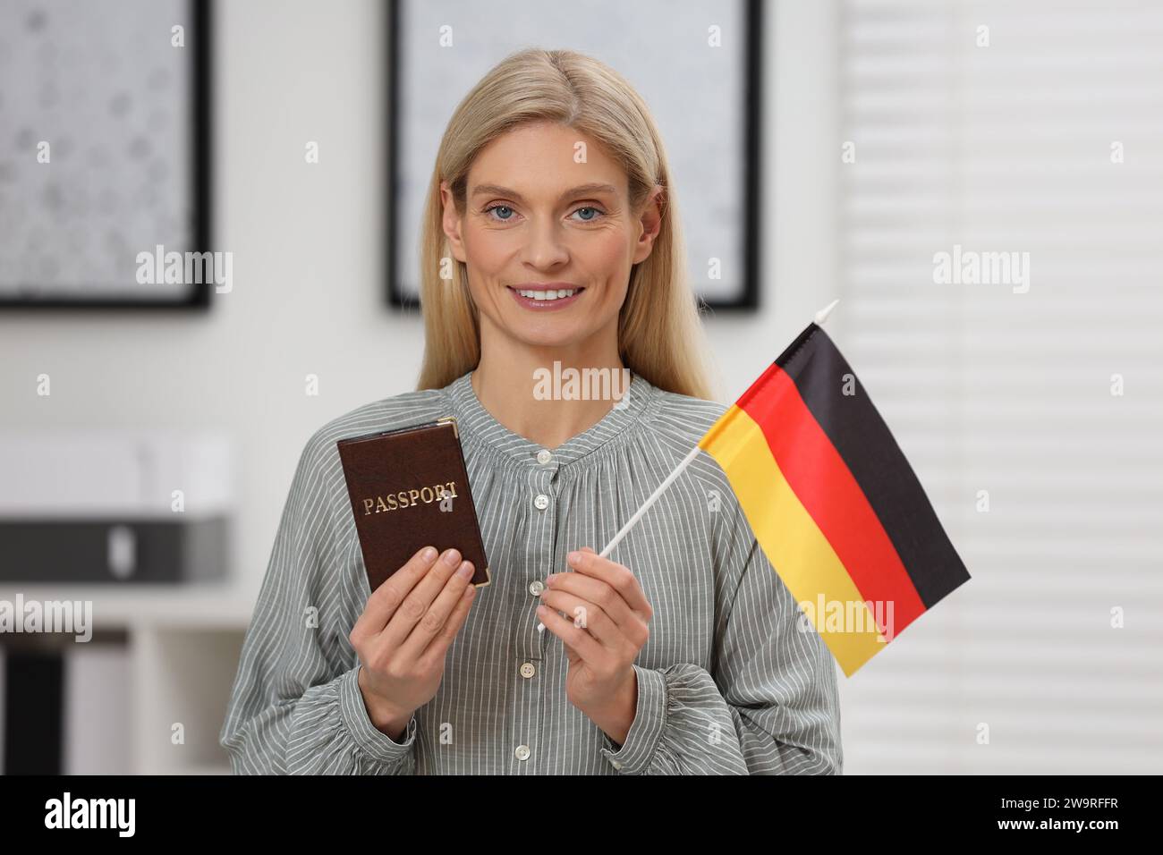 Immigration. Happy woman with passport and flag of Germany indoors ...