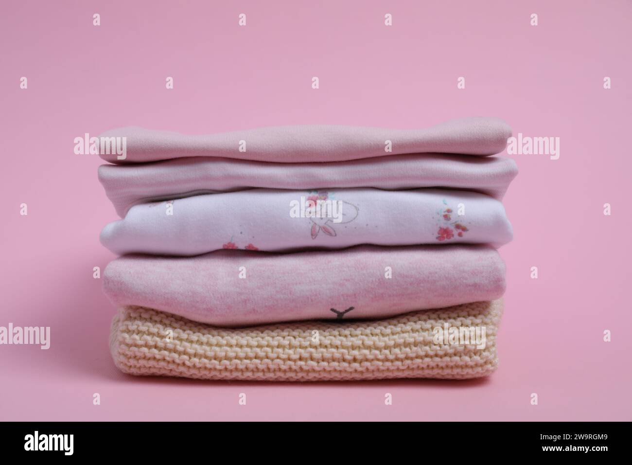 Stack of clean baby clothes on pink background Stock Photo - Alamy