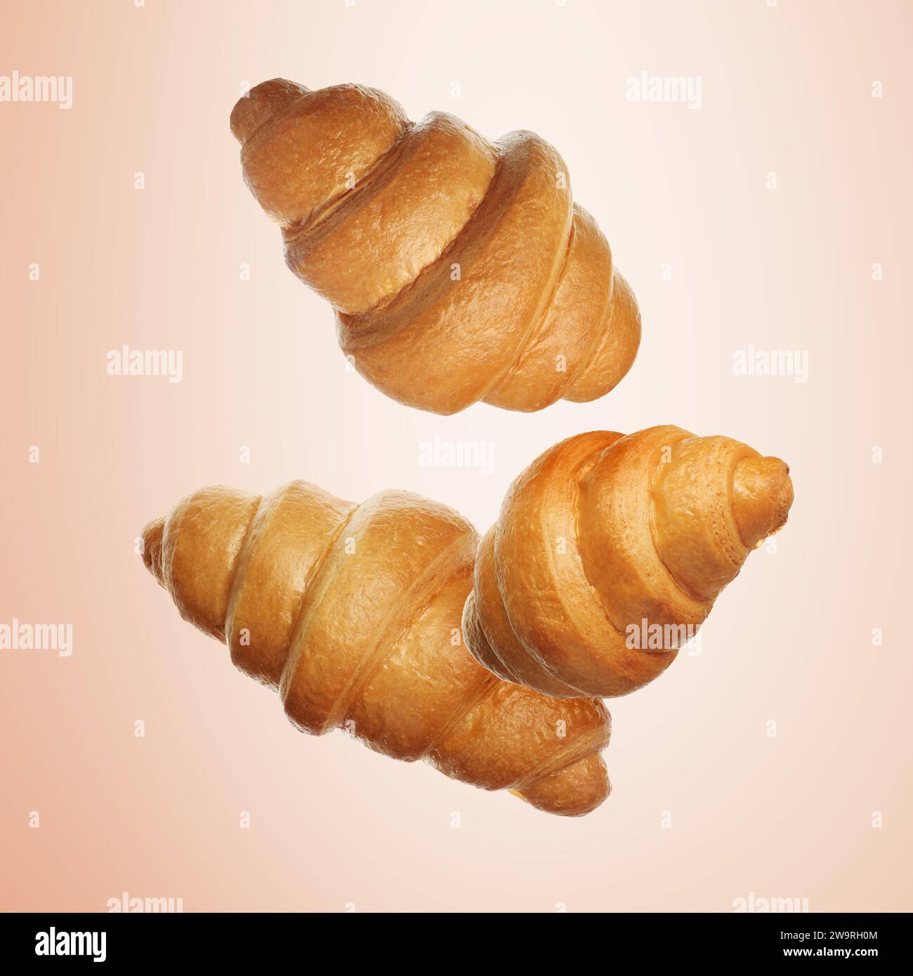 Golden croissants falling on coral gradient background Stock Photo - Alamy