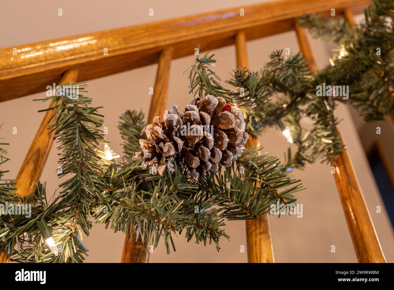 Indoor oak wood staircase railing decorated with holiday evergreen ...