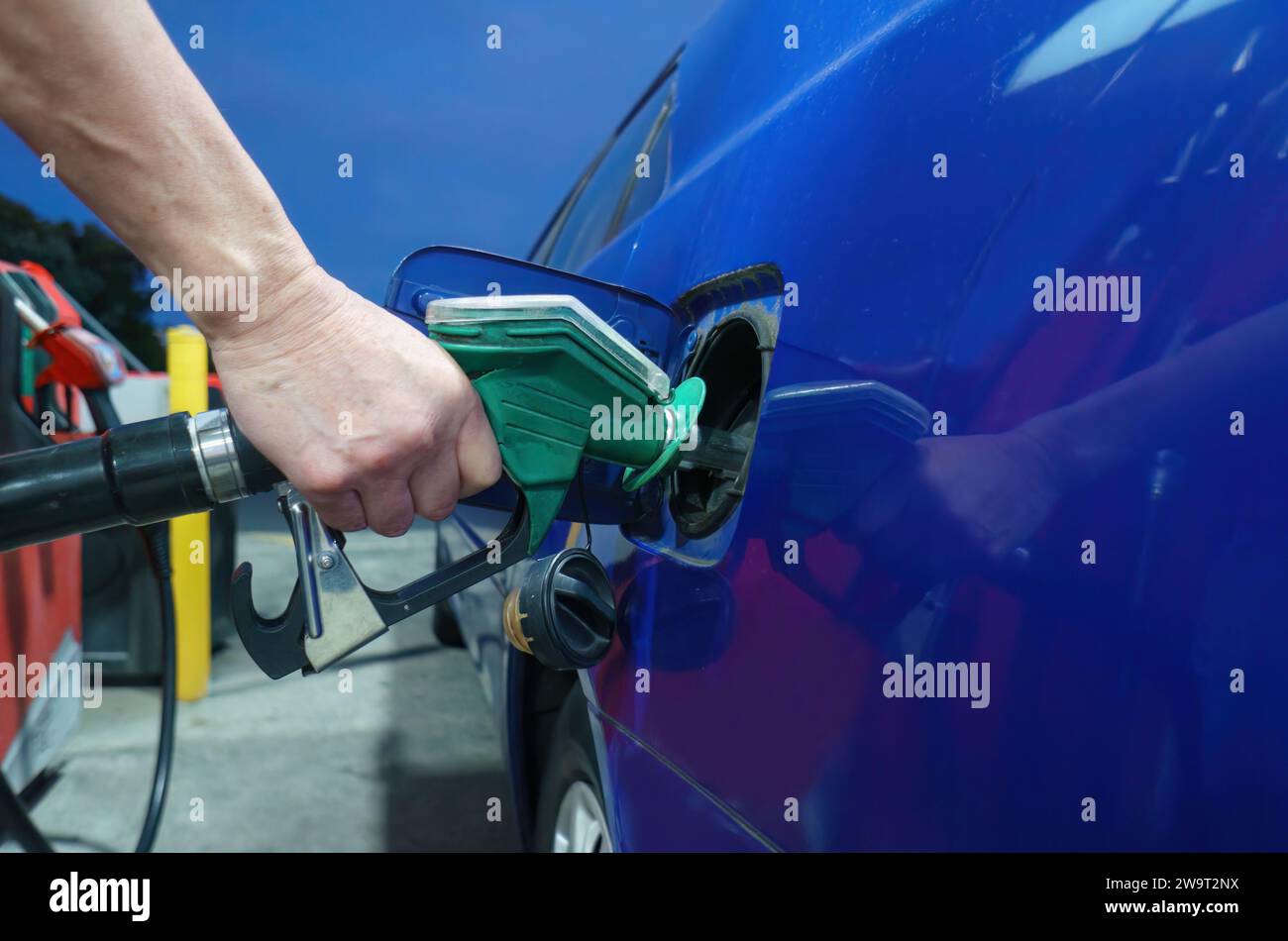 Hand refilling the car with fuel at the petrol station. Blue car at gas ...