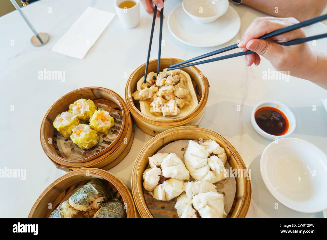 Yumcha, dim sum in bamboo steamers. Hands holding chopsticks. Chinese ...