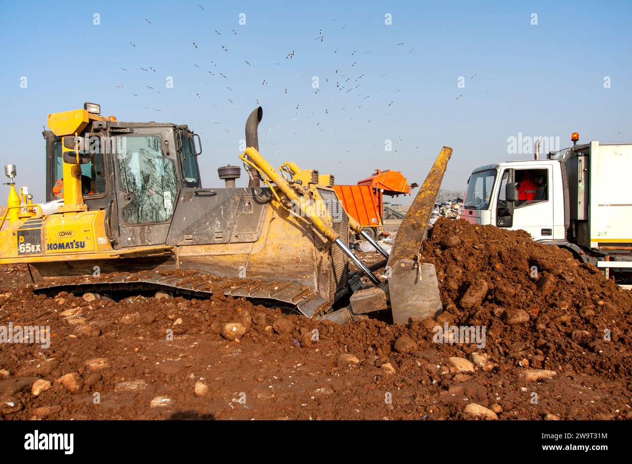 Municipal waste landfill. Workers with trucks and bulldozers at work in ...