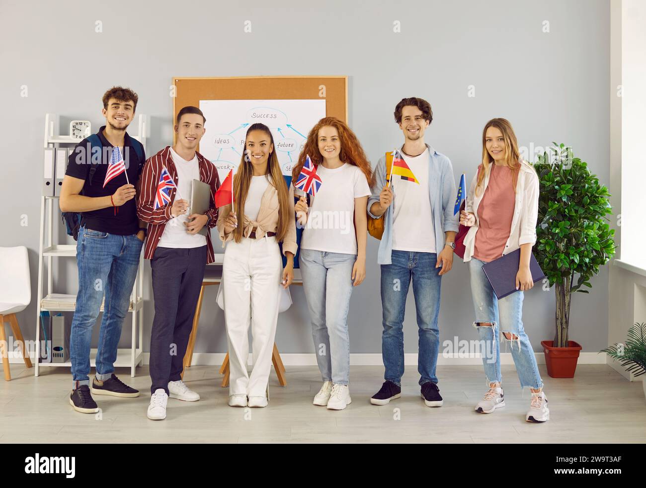 Portrait of happy international students holding flags of different ...