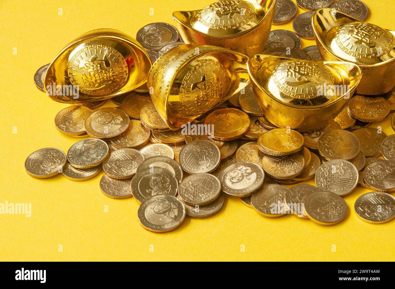 Close up view of golden ingot and coins with yellow cover background ...