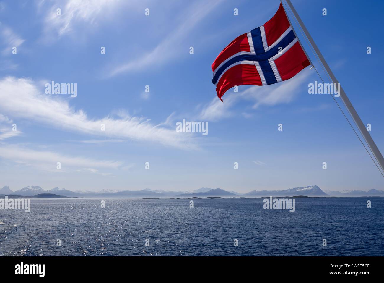 A vivid Norwegian flag billowing against a summer sky, set over a ...