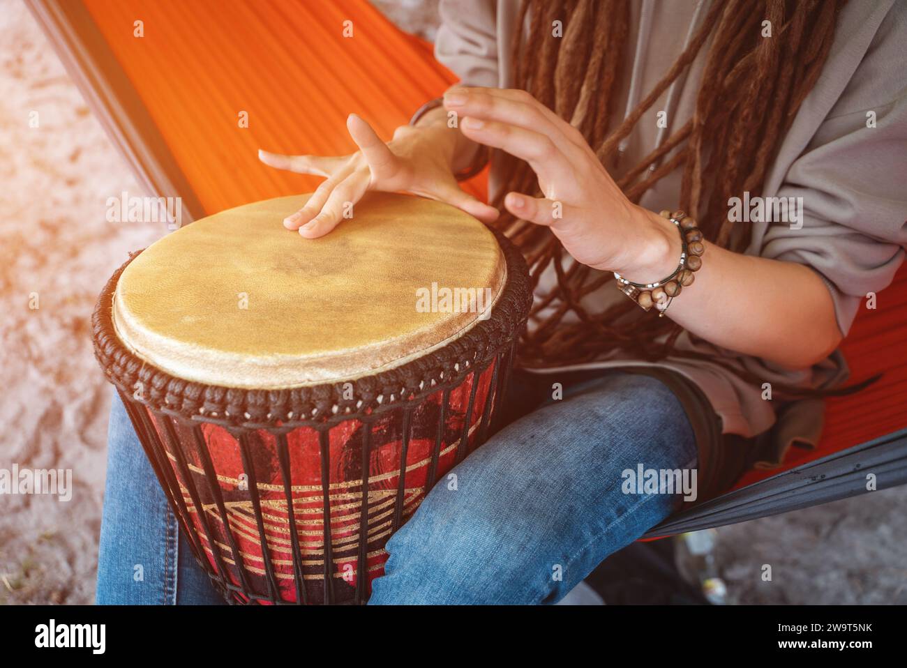 person with dreadlocks play tribal reggae at small African hand drum ...