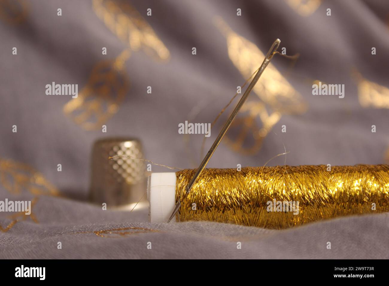 Spool of Metallic Gold Thread on Gray and Gold Chiffon Fabric Stock ...