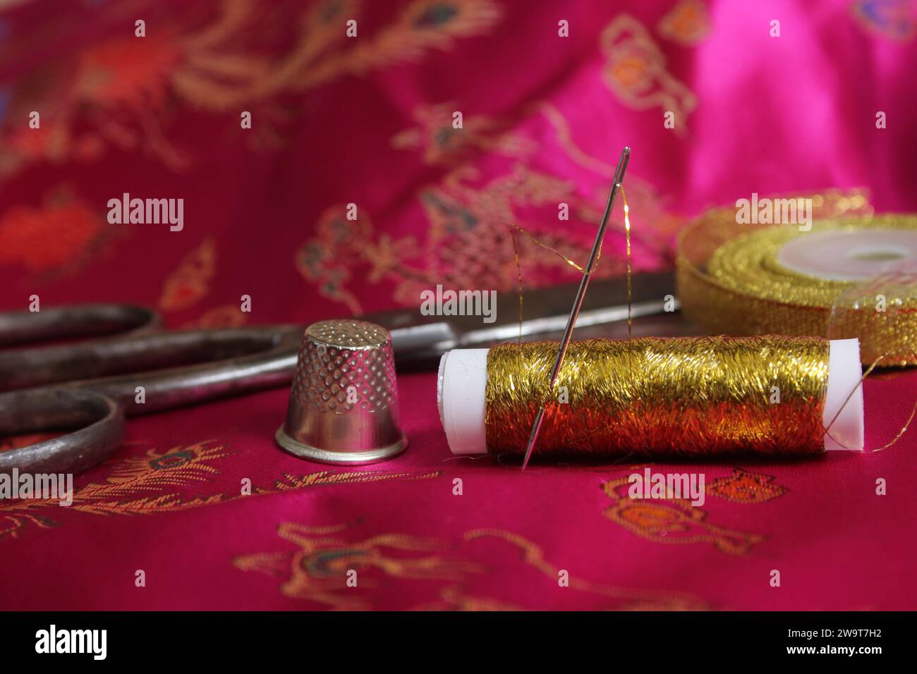Spool of Gold Metallic Thread and Thimble on Vintage Pink Silk Fabric ...