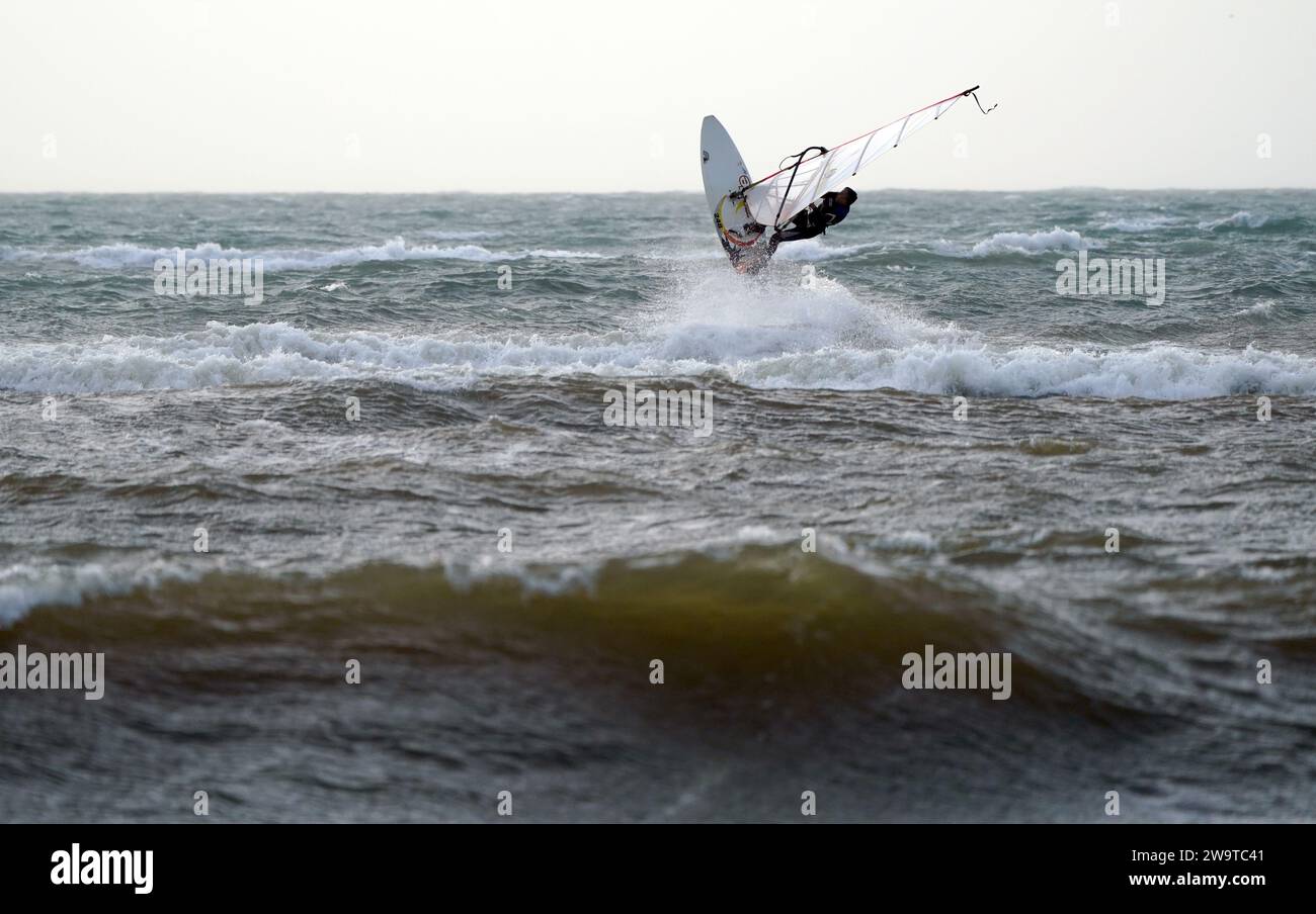 A windsurfer jumps in the air after hitting a wave in the sea off of ...