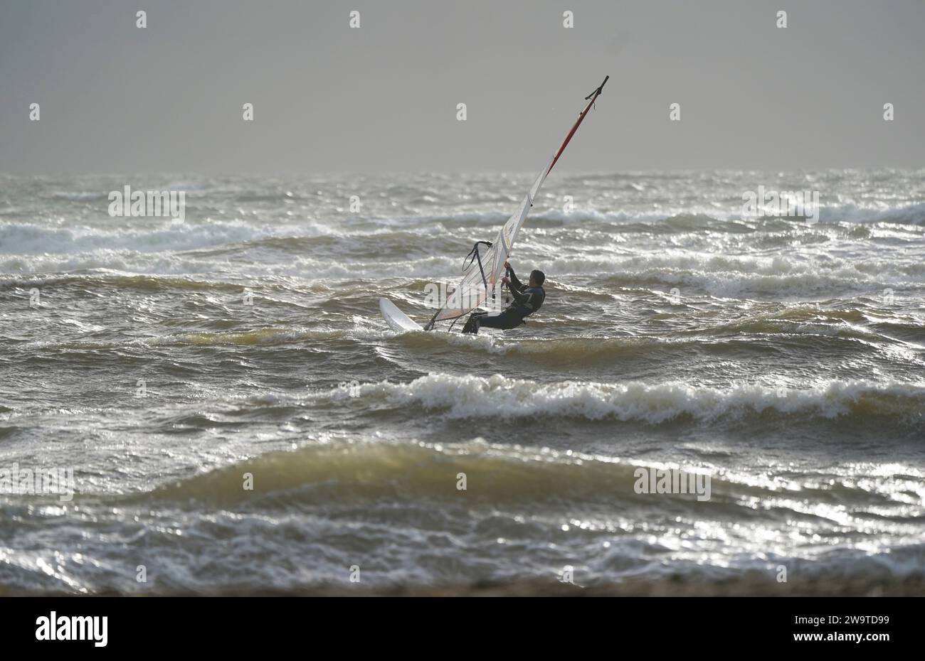 A windsurfer surfs in the sea off of Avon Beach in Dorset. Strong gusts ...