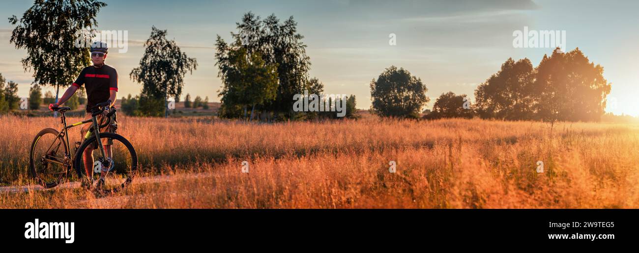 Beautiful panorama of a guy with a gravel bike standing on a path in a ...
