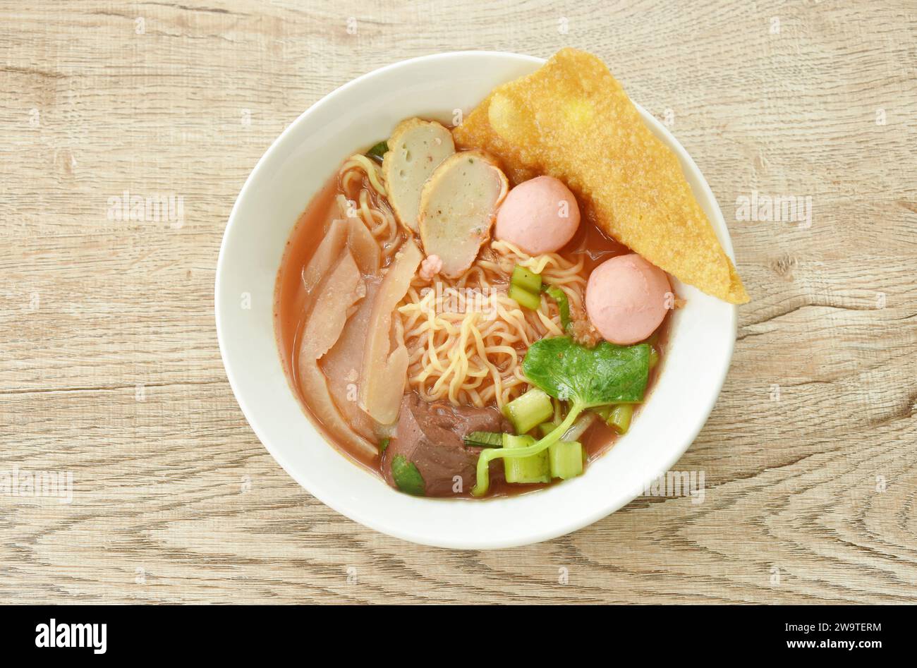 Chinese yellow egg noodles with fish ball and chop pork in red soup on ...
