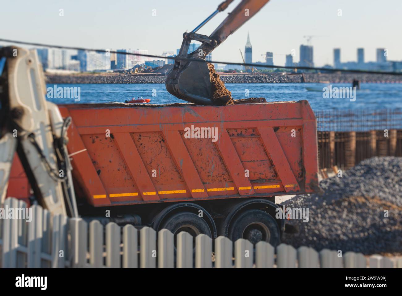 Excavator unloading sand into the dump truck on the construction site ...