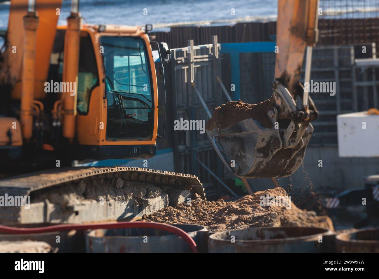 Excavator unloading sand into the dump truck on the construction site ...