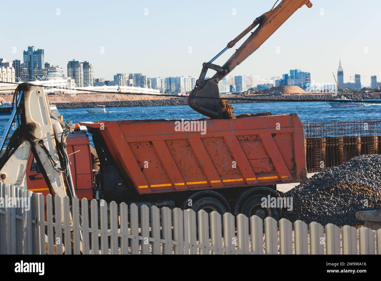 Excavator unloading sand into the dump truck on the construction site ...