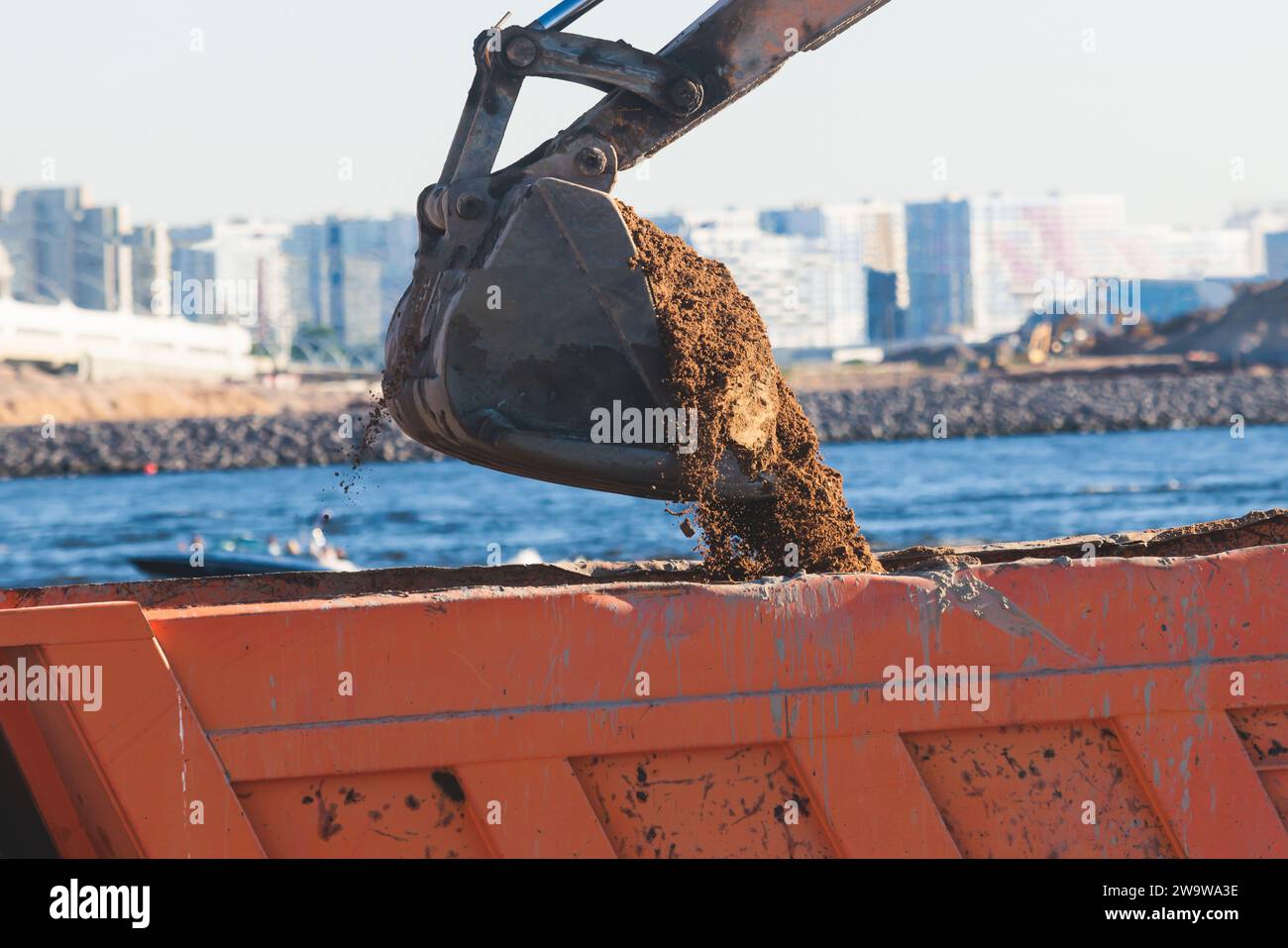 Excavator unloading sand into the dump truck on the construction site ...