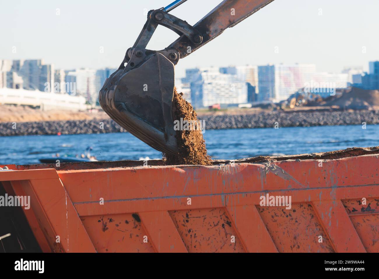 Excavator unloading sand into the dump truck on the construction site ...
