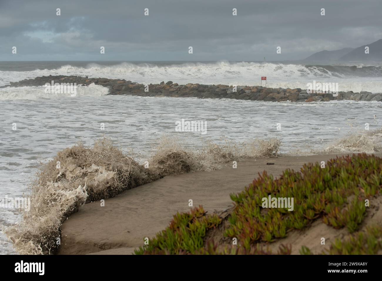 Ventura beach mean high tide line is splashed with sandy ocean water as ...