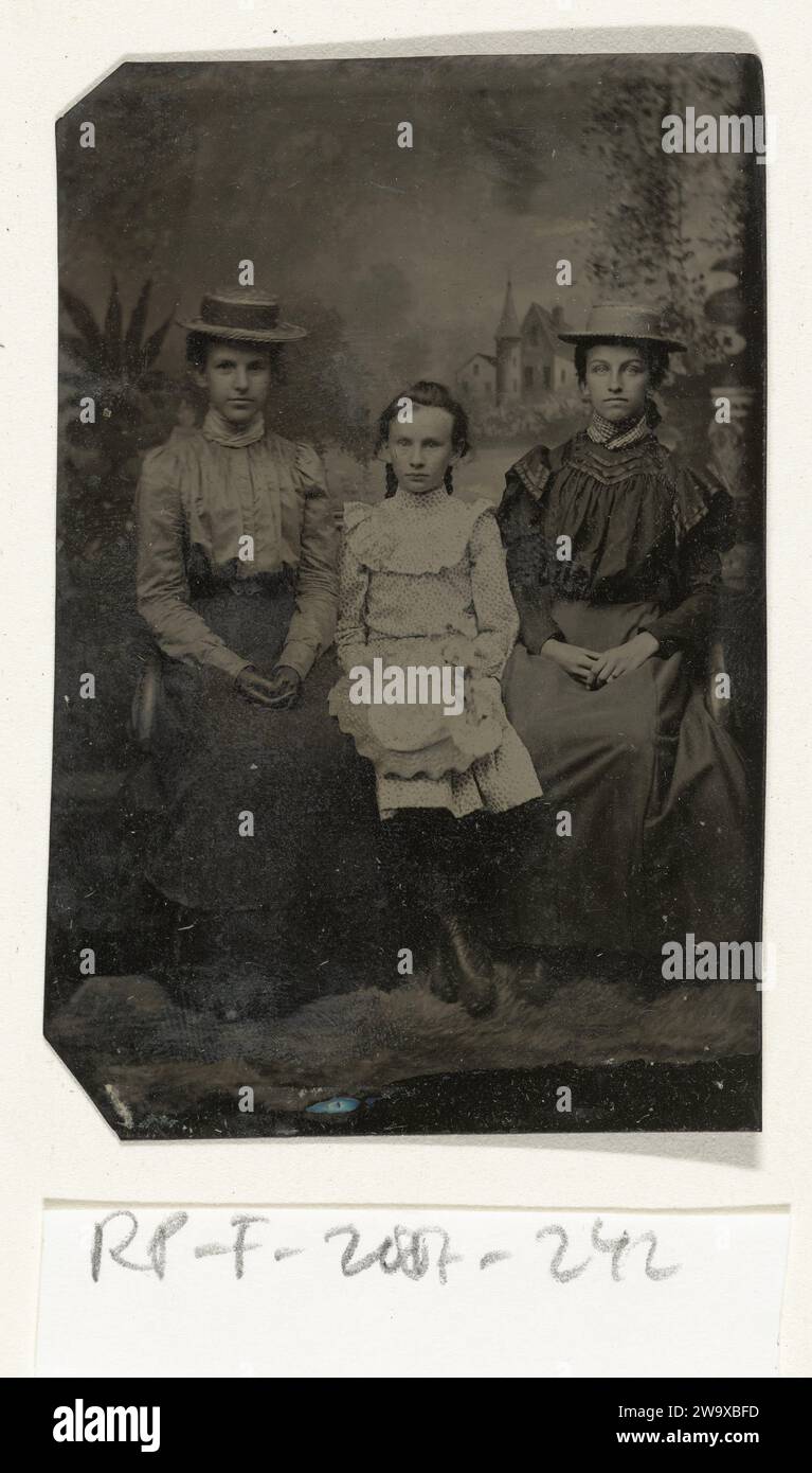 Portrait of two women and a girl, sitting in a studio with painted ...