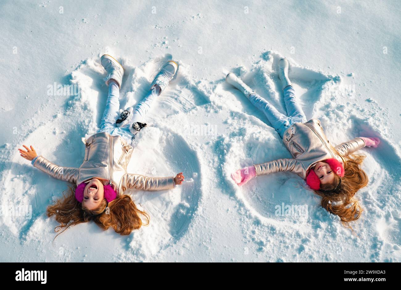 Happy girl on a snow angel shows. Two little girl making snow angel ...