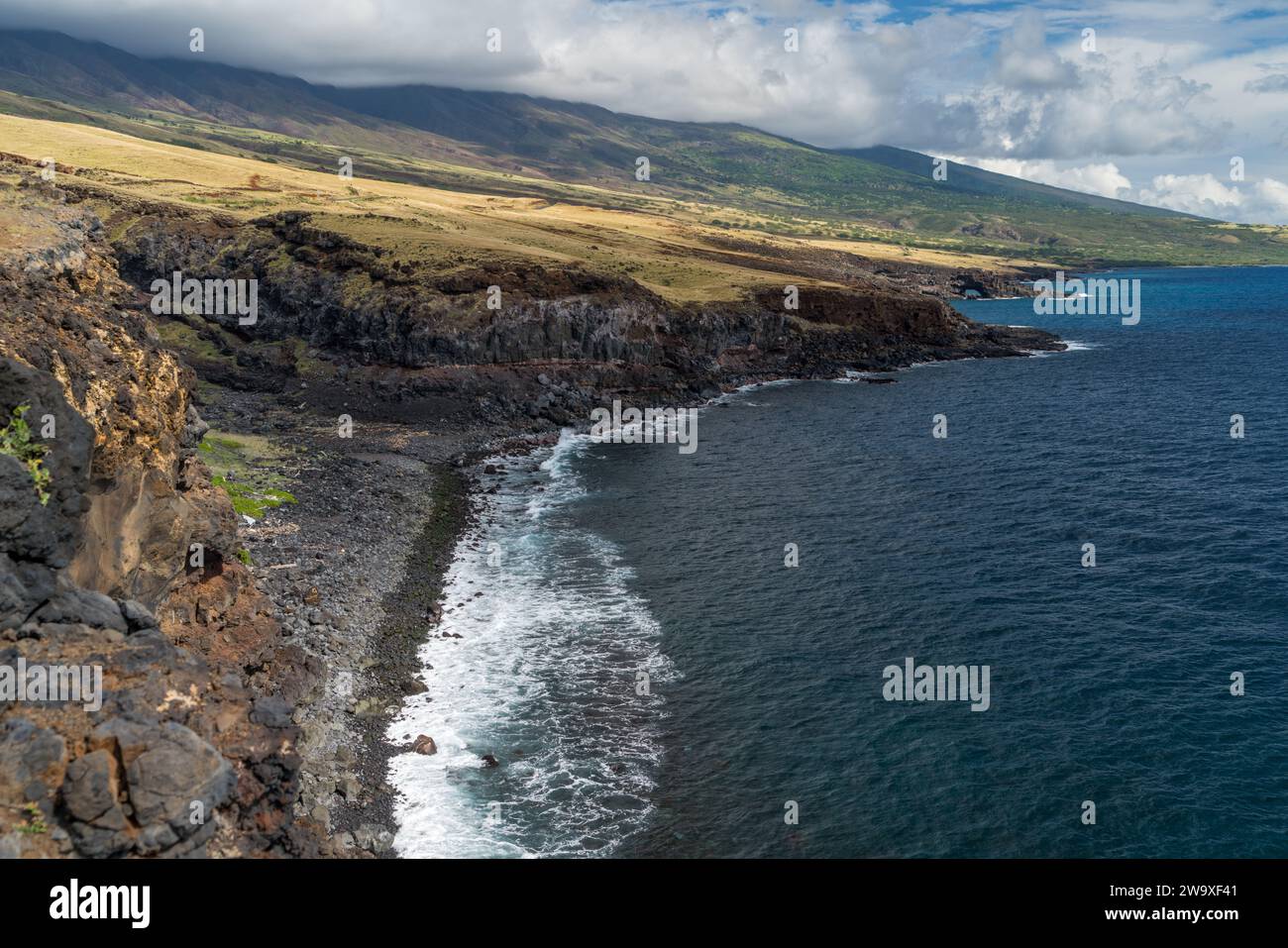 Lava cliffs tower over the deep blue waters of Maui, showcasing the ...