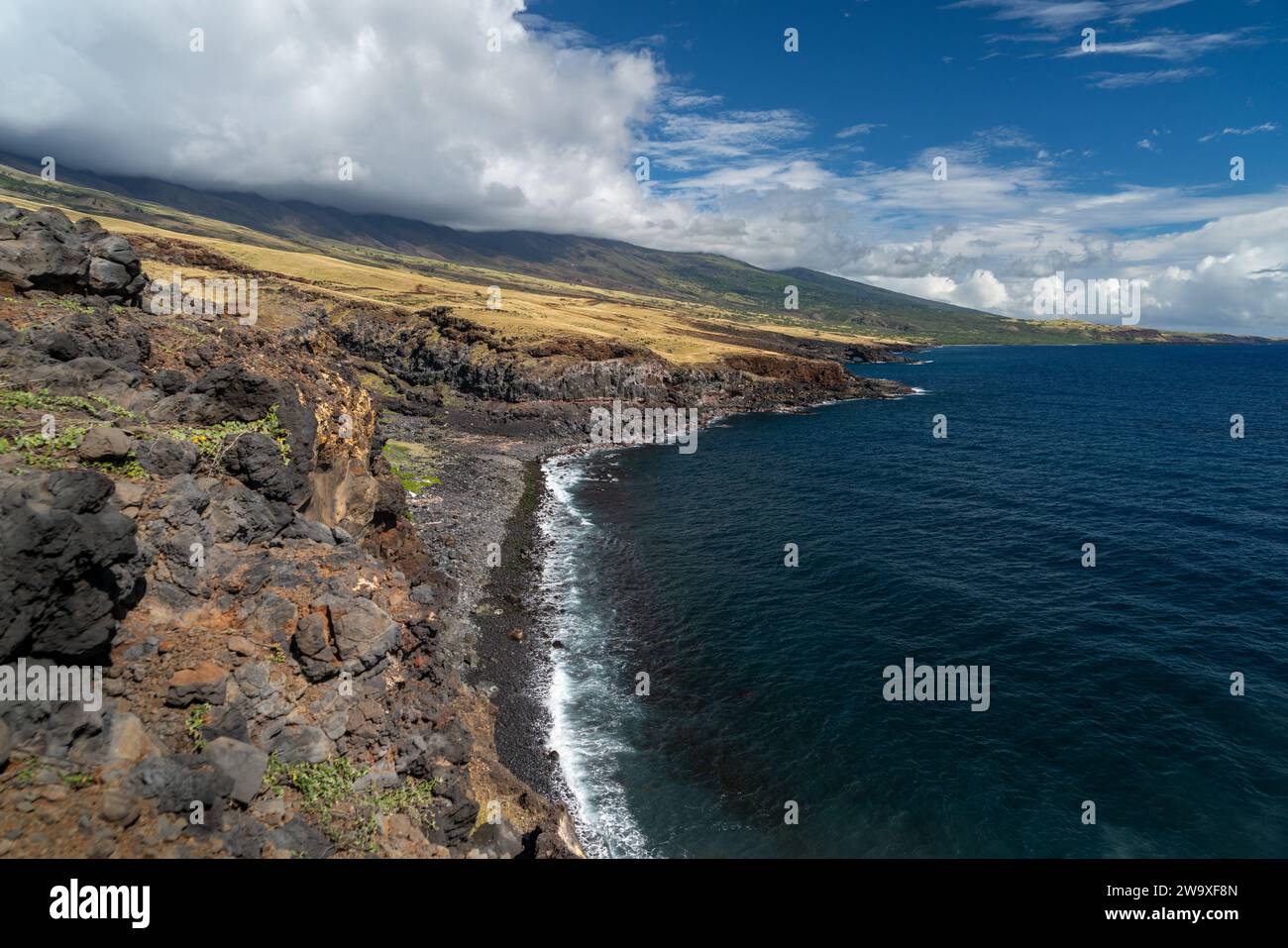 Lava cliffs tower over the deep blue waters of Maui, showcasing the ...