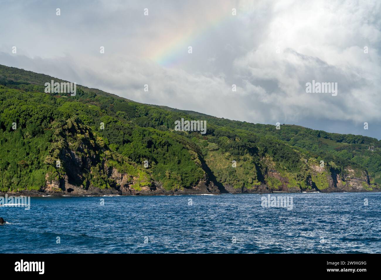 A brilliant rainbow stretches across the sky above the coastal cliffs ...