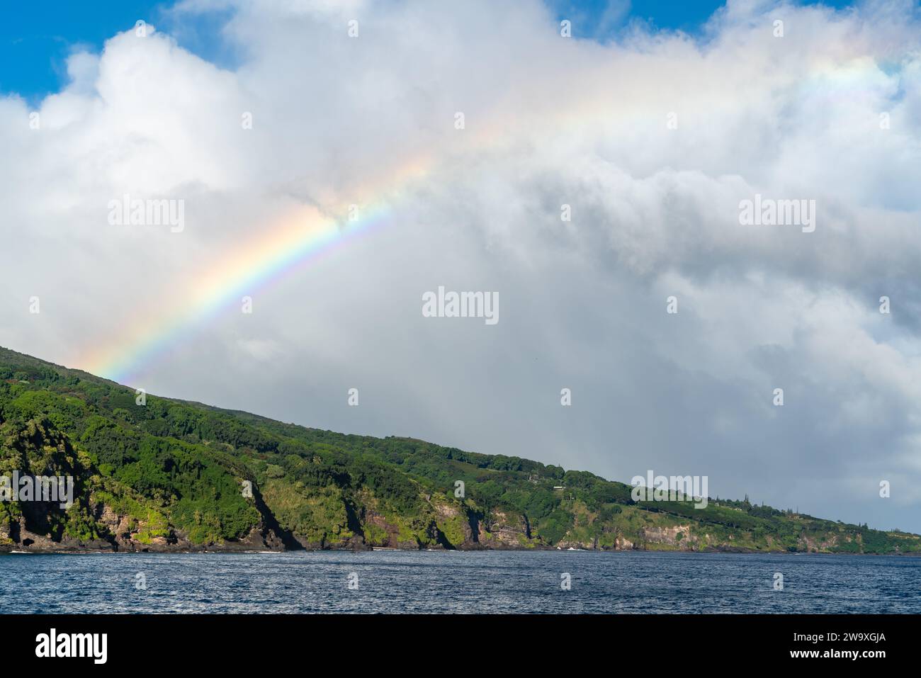 A brilliant rainbow stretches across the sky above the coastal cliffs ...