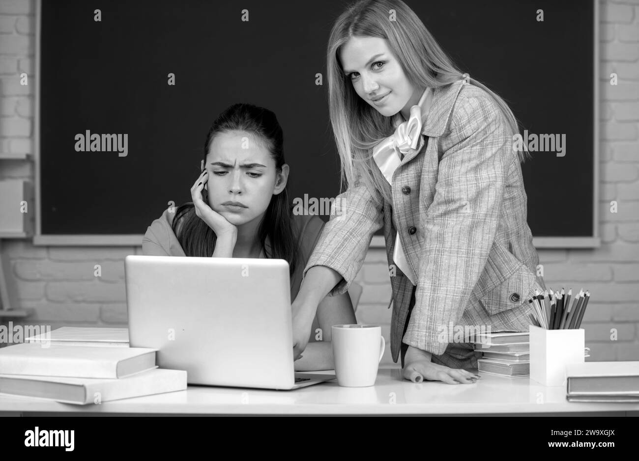 Students girls looking at laptop computer in classroom at school ...