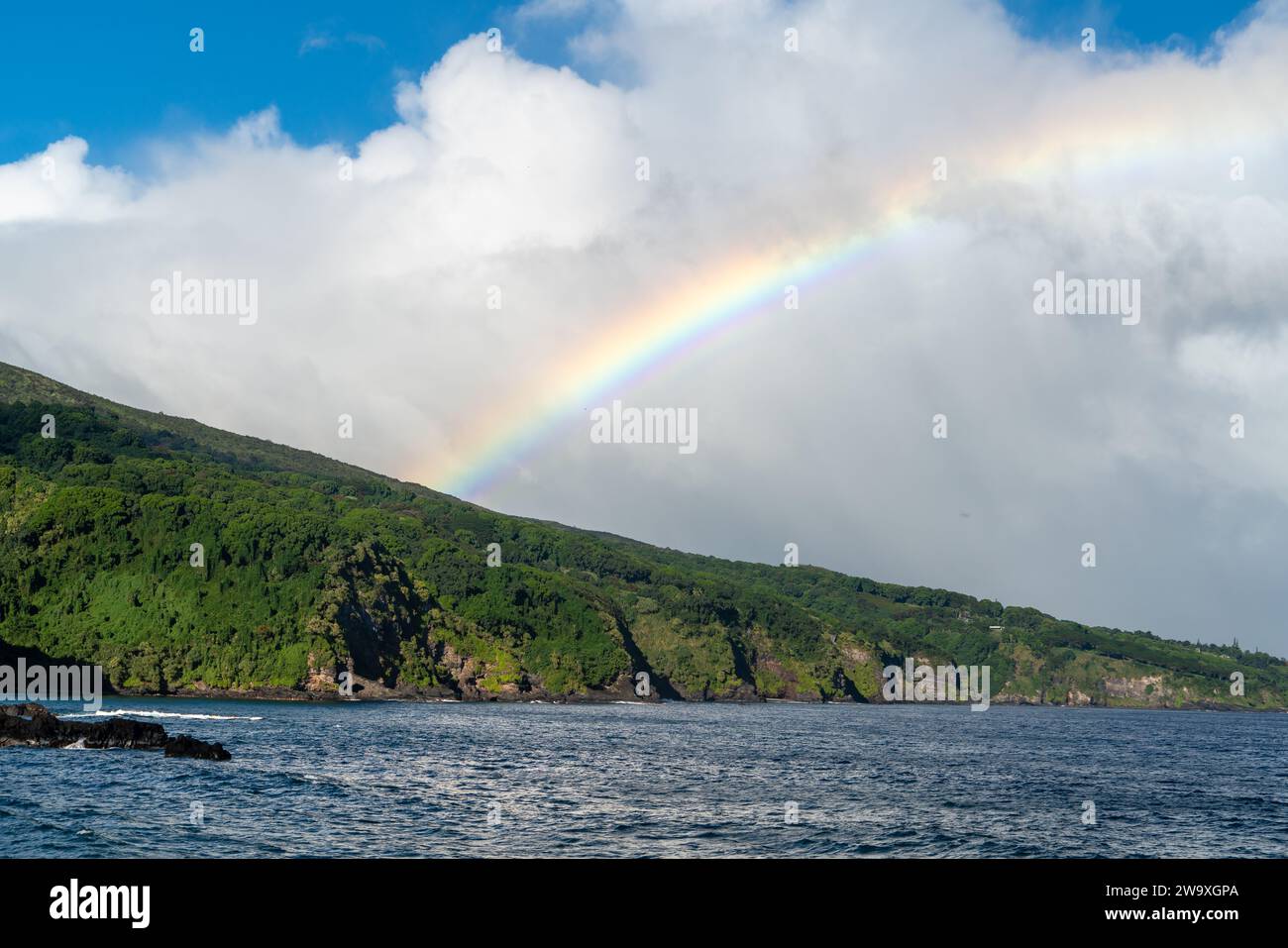 A brilliant rainbow stretches across the sky above the coastal cliffs ...