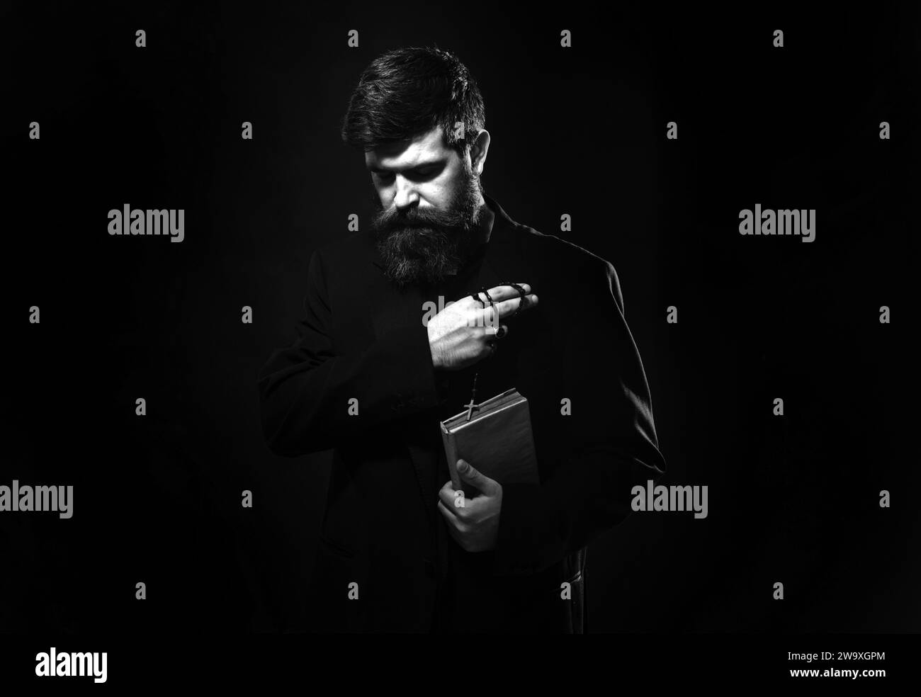Praying hands priest portrait of male pastor. Man in suit with a Bible ...