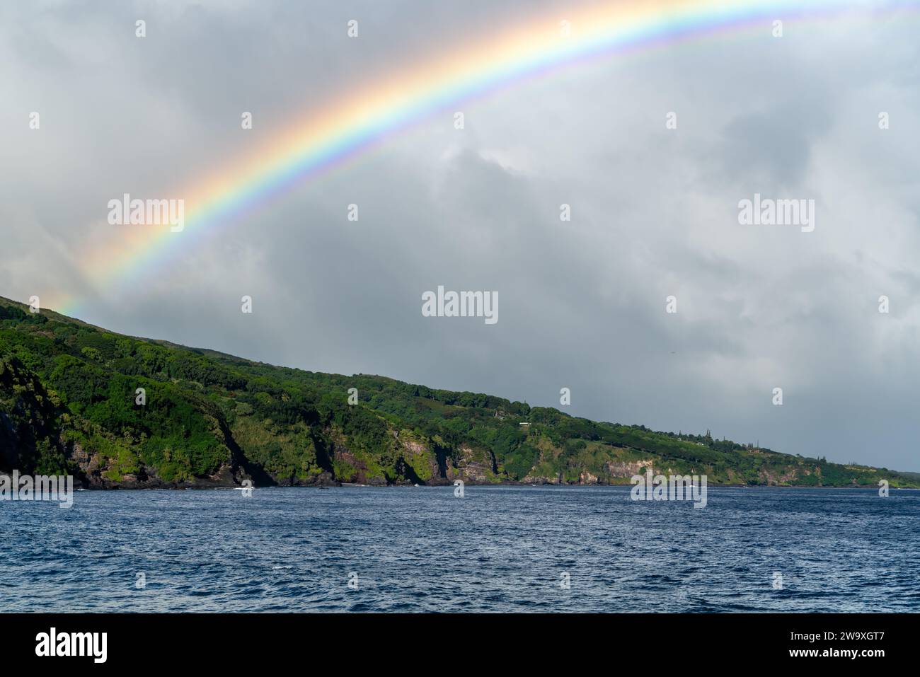 A brilliant rainbow stretches across the sky above the coastal cliffs ...