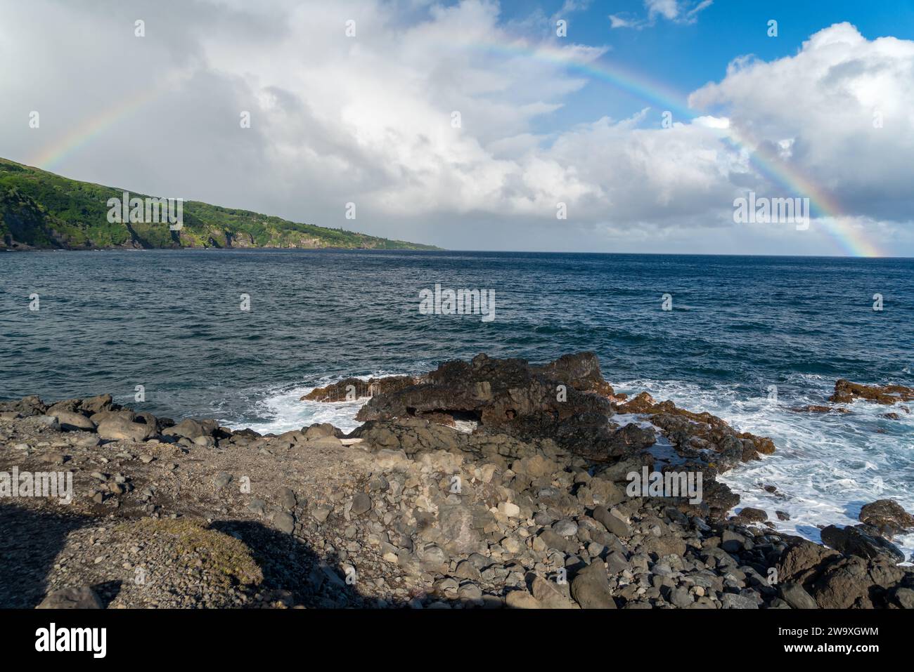 A spectacular full rainbow crowns the ocean's spray along the lava rock ...
