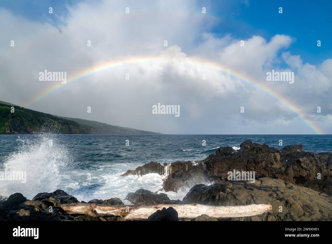 A spectacular full rainbow crowns the ocean's spray along the lava rock ...
