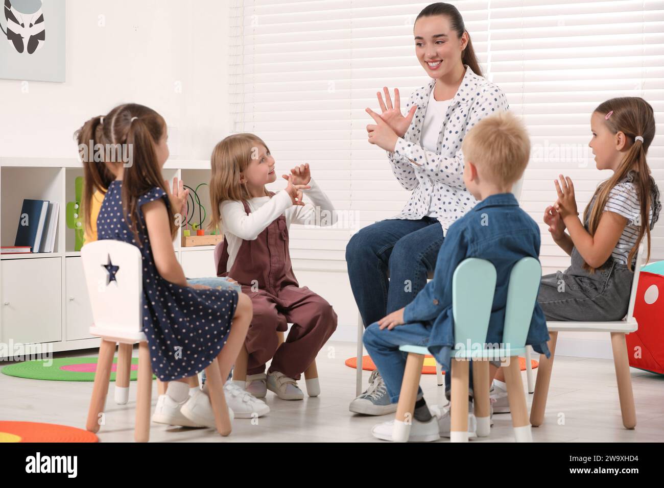 Nursery teacher and group of cute little children learning numbers in ...