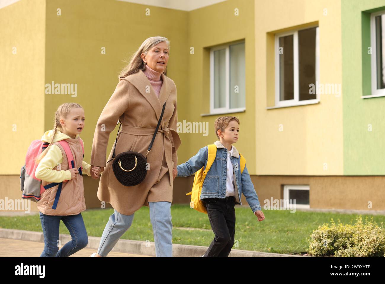 Being late for school. Senior woman and her grandchildren with ...