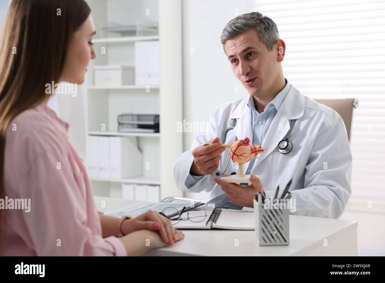 Gastroenterologist with human stomach model consulting patient at table ...