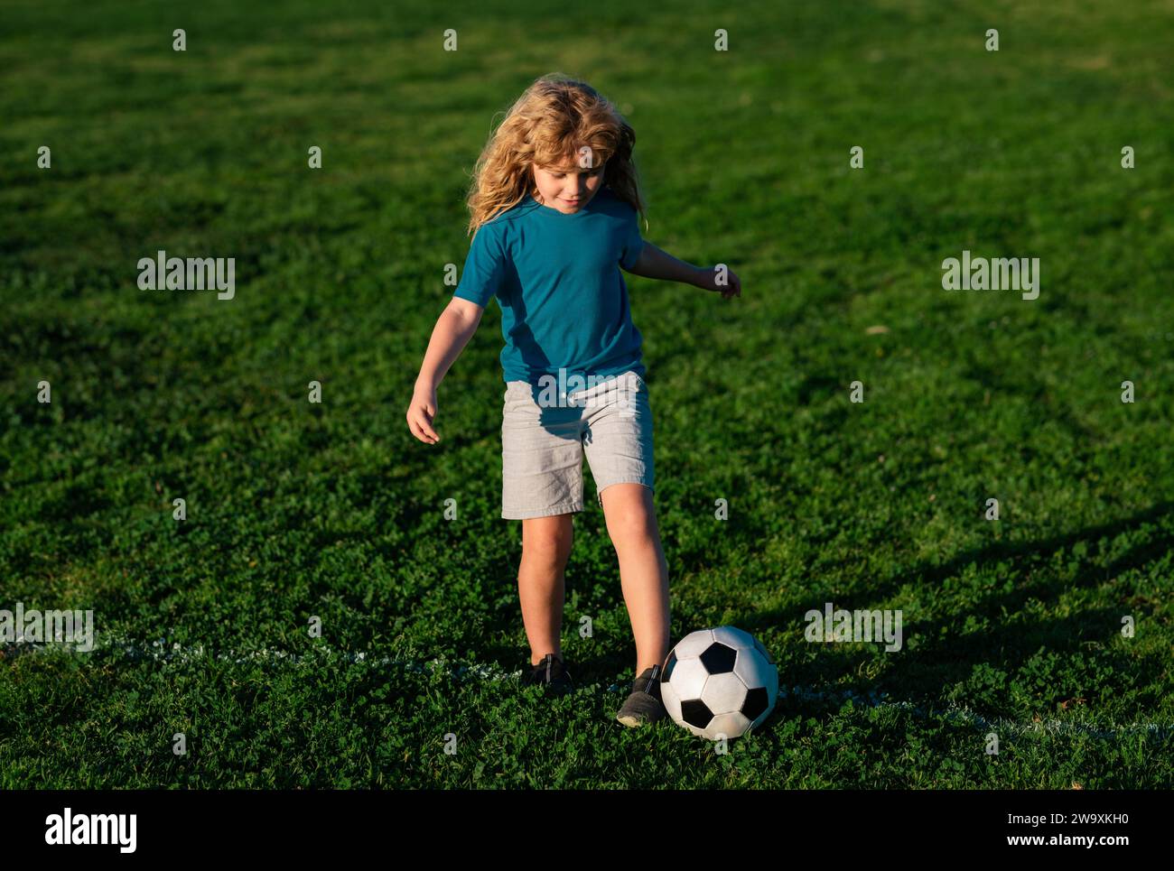 Soccer child play football. Kid kicking a football ball on a grass ...