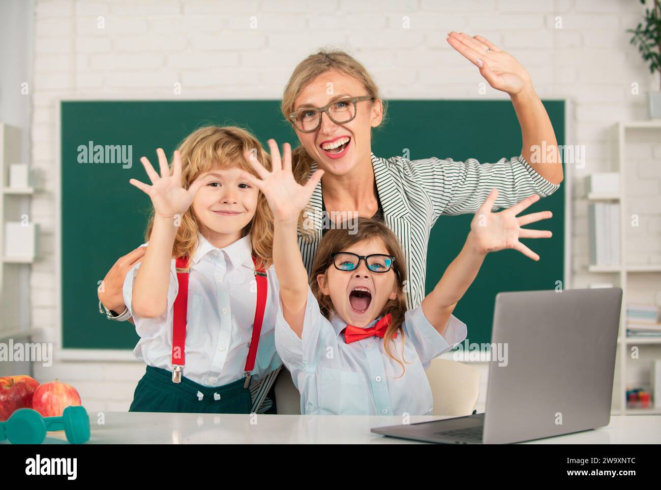 Excited teacher with a school kids learning at laptop computer ...