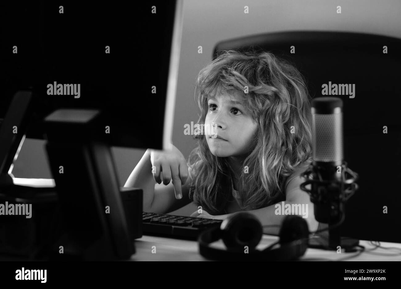 Child learning online at night, using desktop computer in living room ...