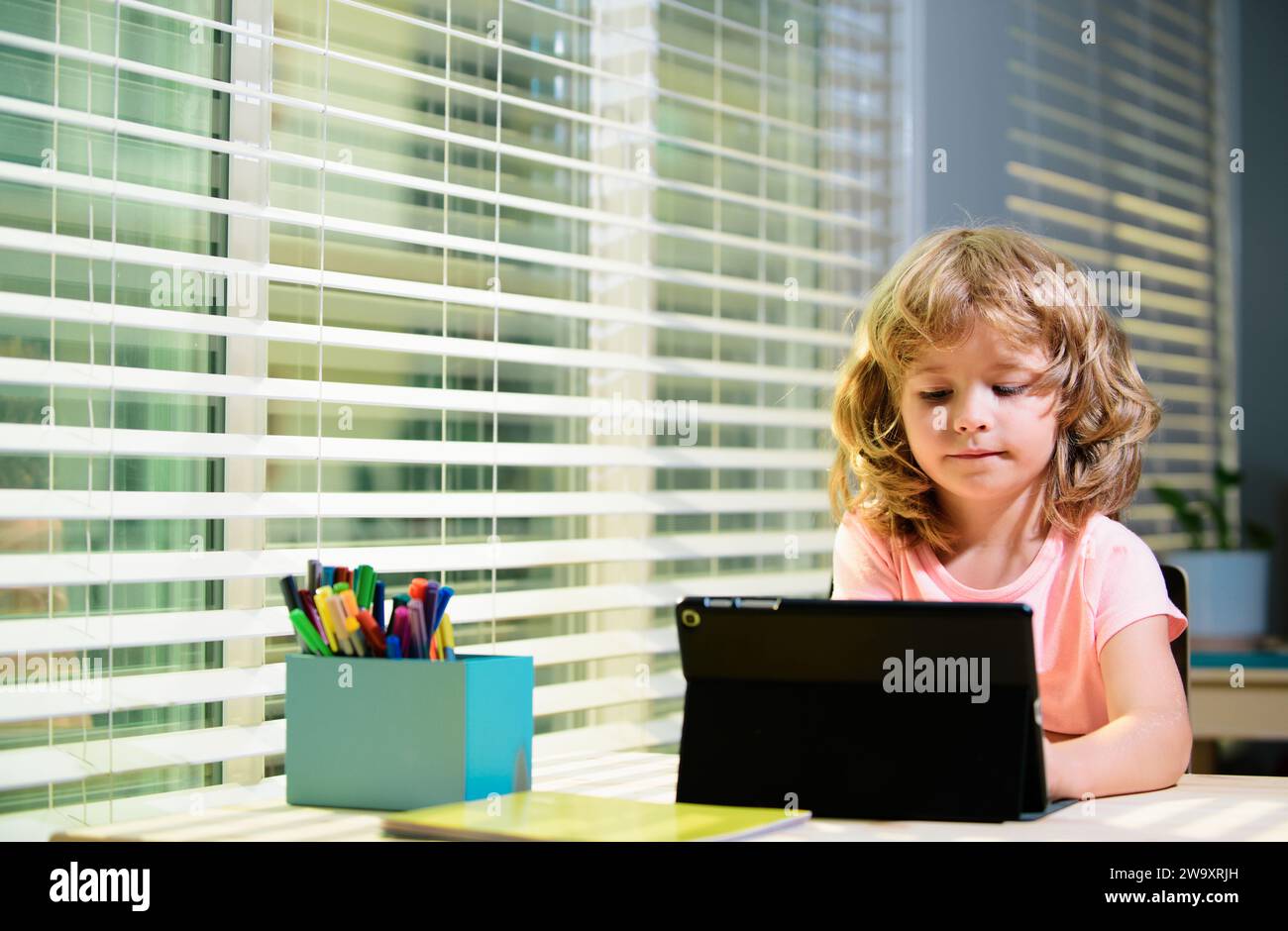 Cute kid boy using tablet on desk at home. Online education concept ...