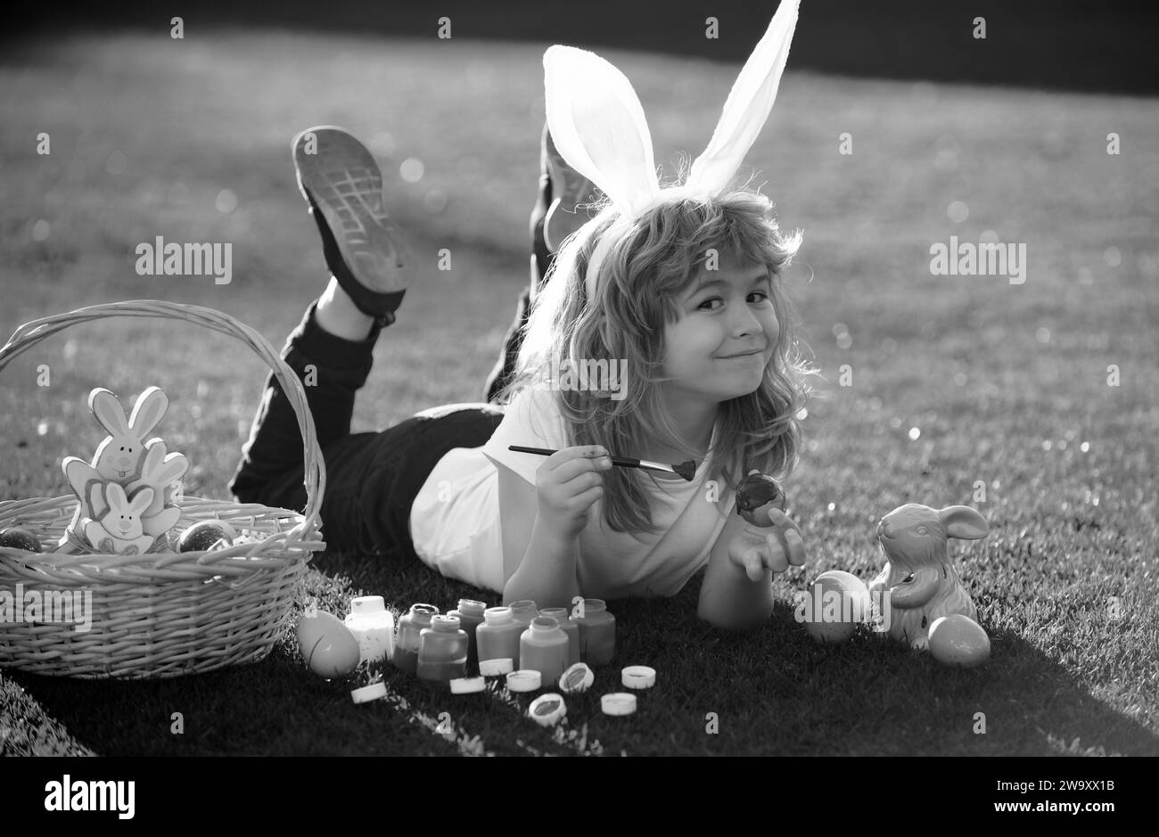Children celebrating easter, painting eggs. Kid in rabbit costume with ...