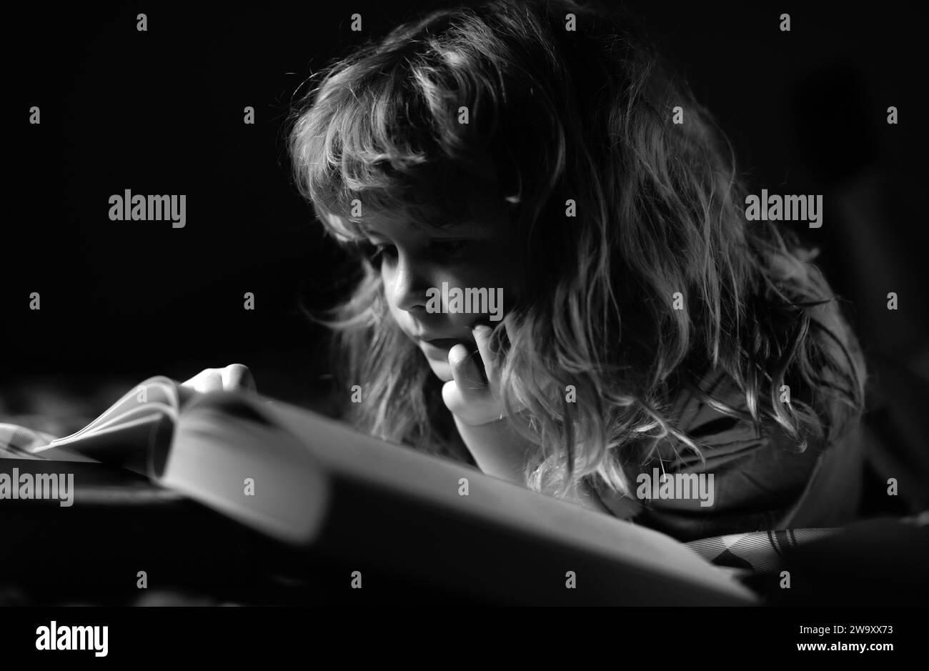 A little cute boy reading a book lying on the bed. Development of the ...