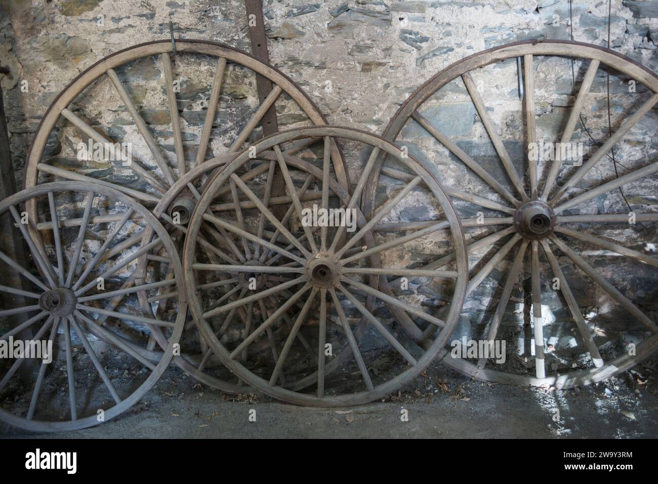 Antique wagon wheels resting against an old stone wall and resting on a ...