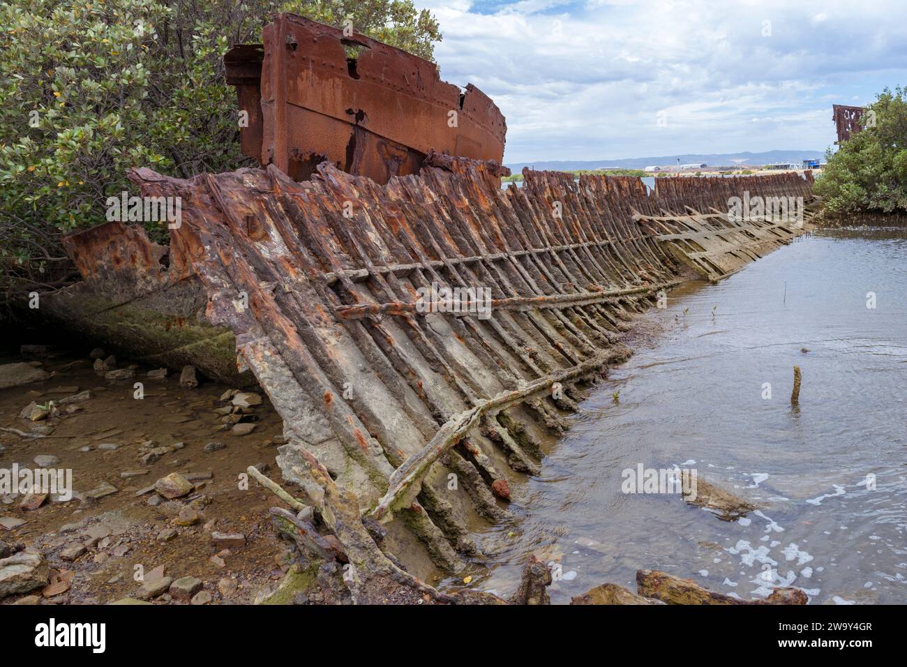 The corroding shell of a steel hulled ship wreck partially submerged at ...